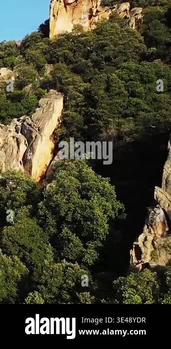 Aerial view of dramatic rock formations rising above dense green forest ...