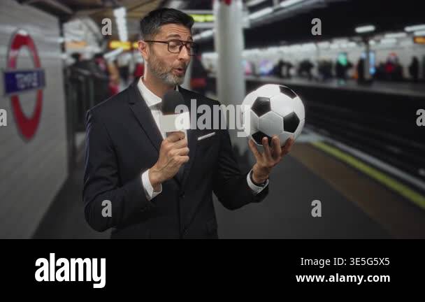 Man reporter holding microphone and soccer ball in a station building ...