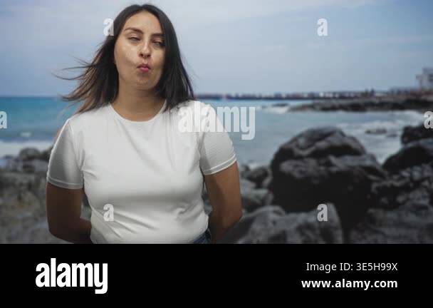 Woman with puckered lips and windblown hair poses with hands behind ...