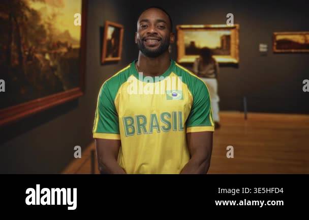 Man smiling in a yellow brazil jersey showing a flag while standing in ...