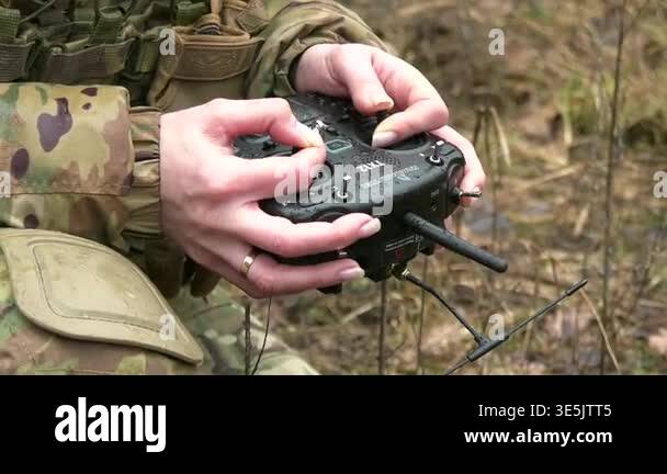 Close-up of the remote control in the hands of a woman in military ...