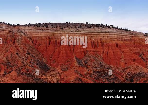 Distancing from layered ridged red rocks with scarce vegetation ...