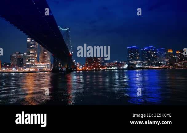Dark river waterscape reflects the lights of the lively city. New York ...