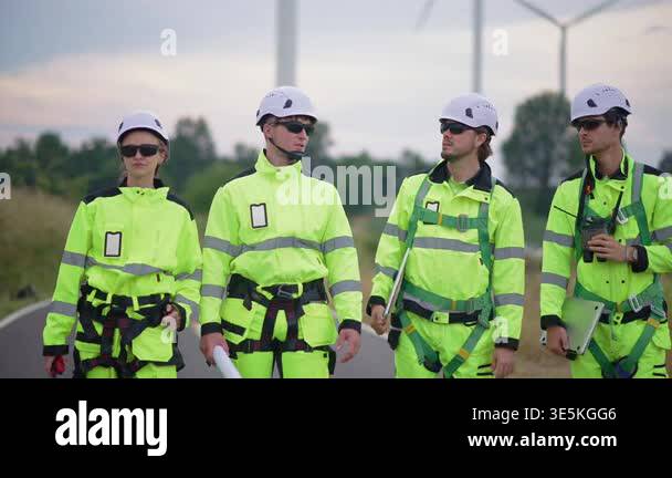 Engineers wearing safety helmets inspecting a wind turbine at a wind ...