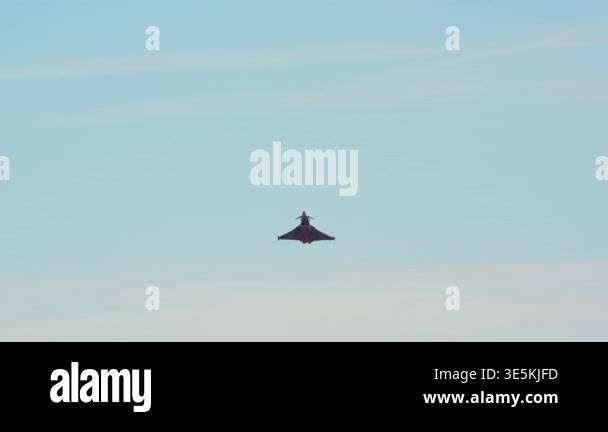Military fighter jet flies towards the camera against a clear blue sky ...
