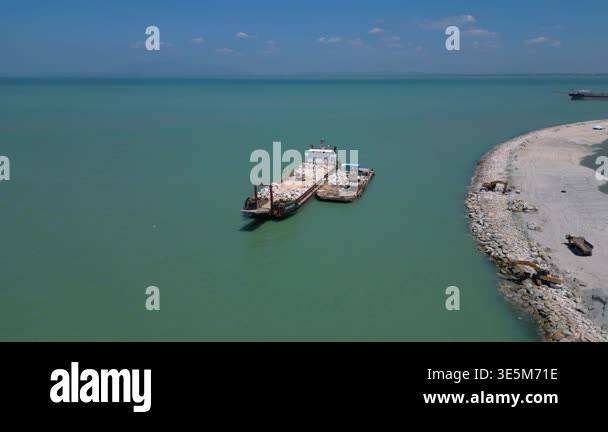Cargo ships moving construction materials along a coastline with land ...