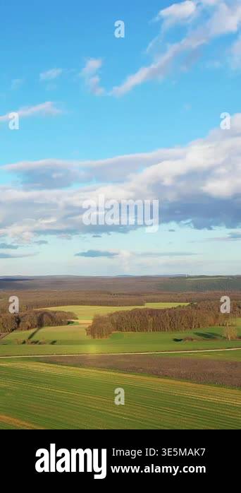 Expansive rural landscape with green fields, wooded areas, and a bright ...