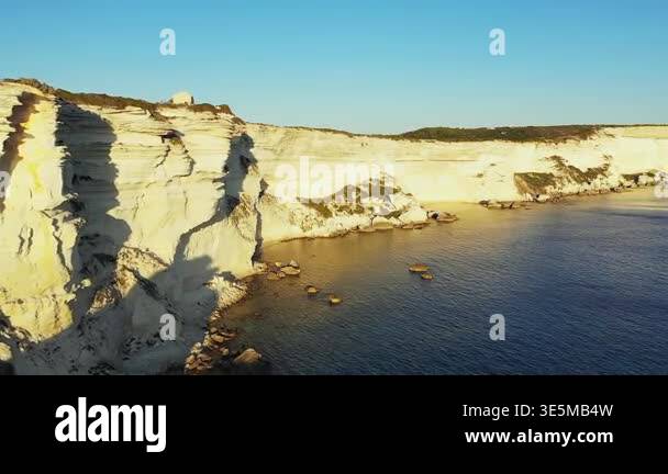 Dramatic white limestone cliffs rise above the clear blue sea along the ...