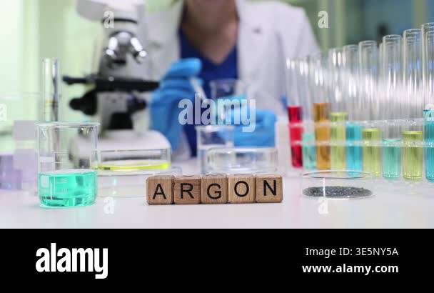 Wooden blocks spell word Argon near colorful test tubes and microscope ...