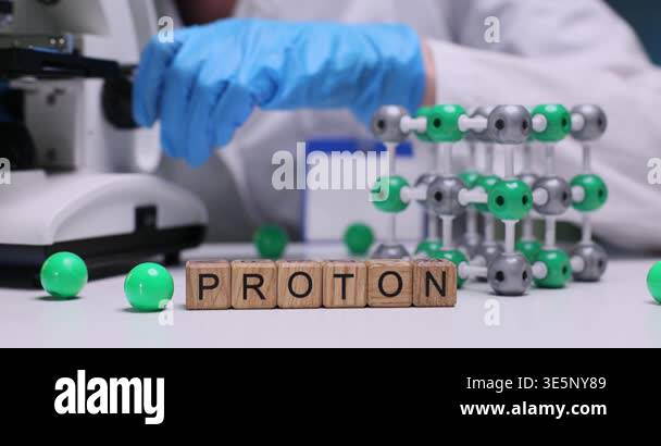 Wooden blocks spell word Proton near molecule model and lab tools ...