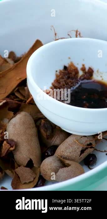 Fresh tamarind with shells in green bowl, white plate with peeled ...