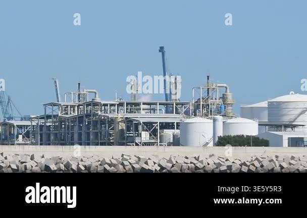 Smoky oil refinery complex, metal structures, storage tanks on a pier ...