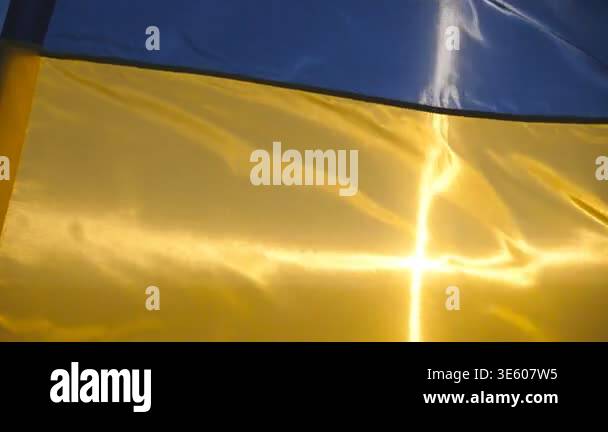 Ukrainian flag waving at wind against the background of sunlight. Blue ...
