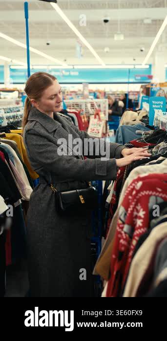 A young beautiful woman selects clothes for her boyfriend in a clothing ...