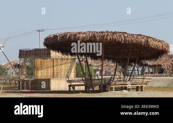 Open-air bamboo seating area shaded by a large thatched roof structure ...