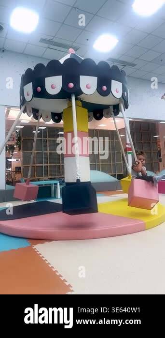 Child riding a soft carousel in indoor play area. Fun activity in kids ...