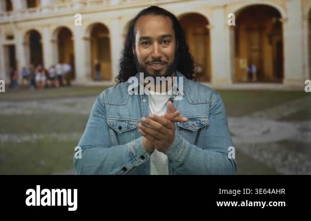 Man clapping hands in a historic building courtyard wearing denim ...
