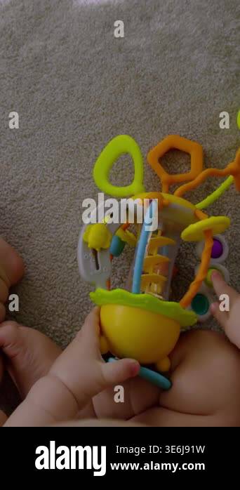 A baby interacts with a vibrant toy, grasping and turning different ...