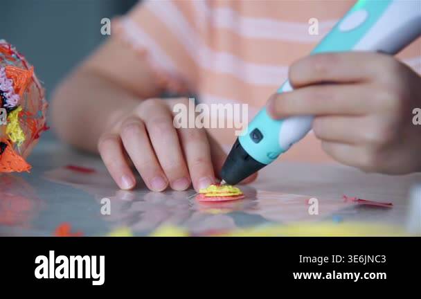 Close up of little girl hands using 3d pen to create plastic shape on ...