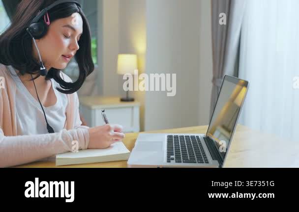 Woman writing notes while using laptop Stock Video Footage - Alamy