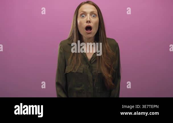 Woman gasping with open mouth in pink studio set, frontal pose wearing ...