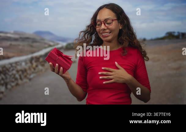 Woman holding red gift box in one hand and hand to chest for thanks on ...