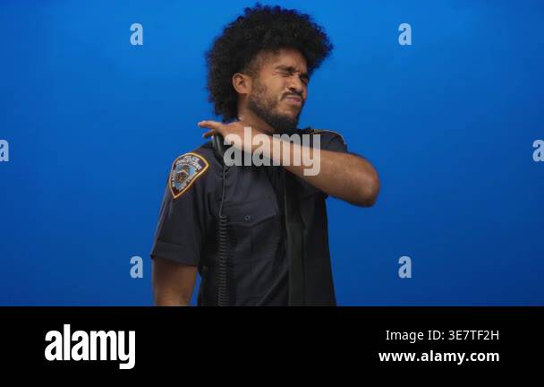 Police officer in uniform standing against blue background grimacing in ...