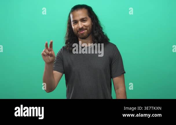 Man with long curly hair and beard showing peace sign with right hand ...
