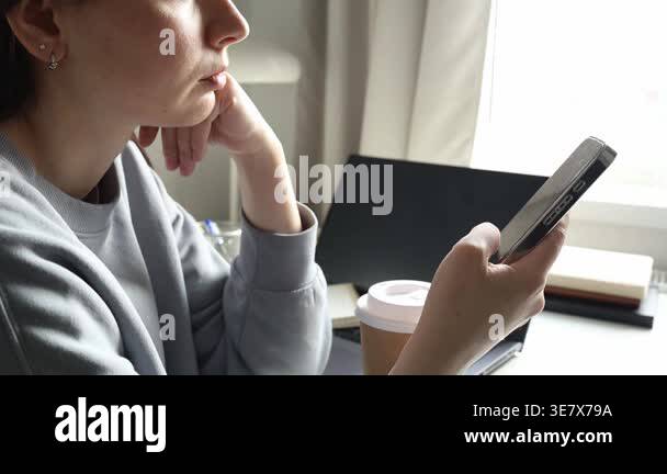 Bored and sad young woman staring at her smart phone and slowly ...