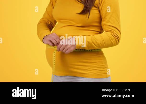 A woman with light skin is standing and using a tape measure around her ...