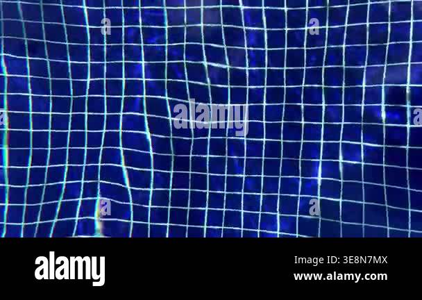Blue mosaic tiles on the bottom of the pool, water waves create ...