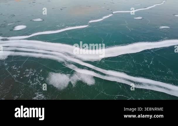 Aerial view orbits around a person walking across frozen Abraham Lake ...
