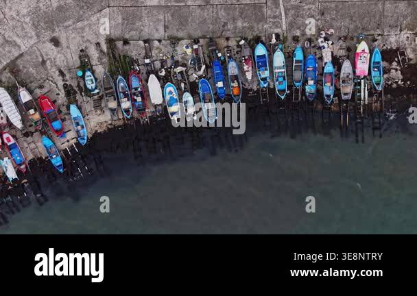 Boats are arranged in a row along the shore. The water is close to the ...