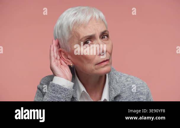Portrait of an older woman cupping her ear and leaning forward ...