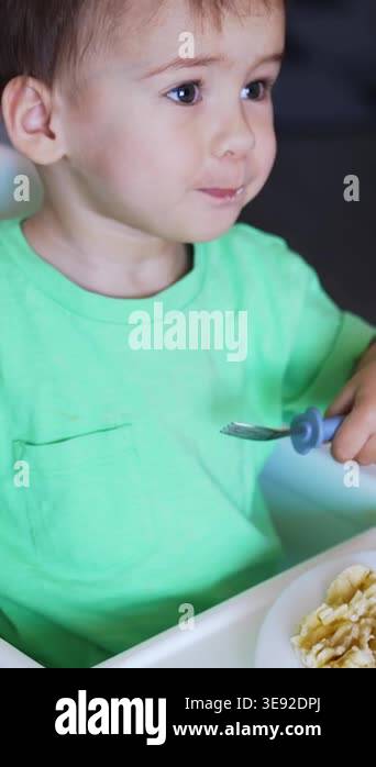 One year old toddler eating porridge. Mom gives a spoon to her son and ...