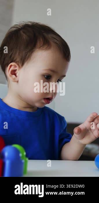 Beautiful baby boy in blue t-shirt sits at desk. One year old toddler ...