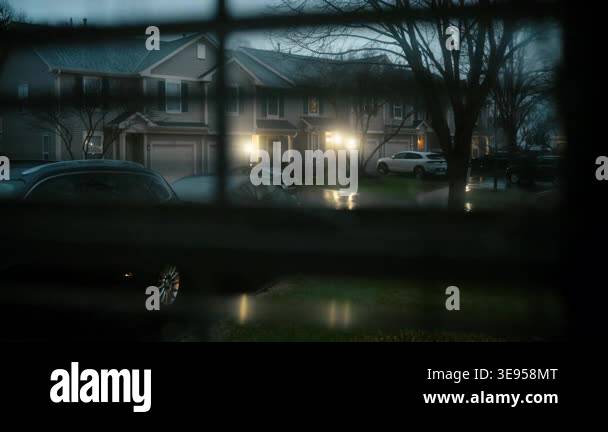 Rainy suburban neighborhood viewed through window blinds. Wet street ...