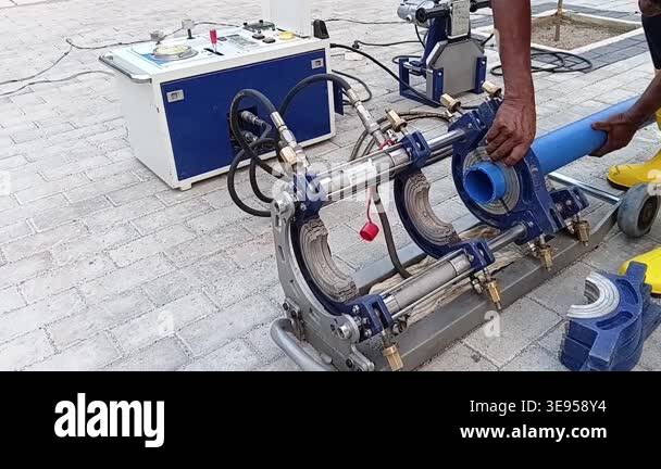 Close up of an industrial plumber clamping a large blue plastic pipe ...