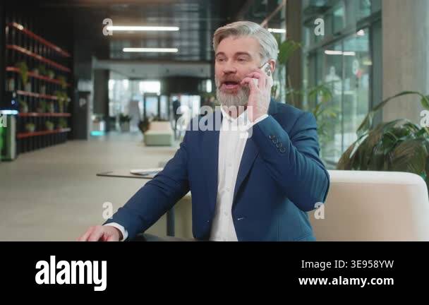 Happy mature businessman in suit answering to client on mobile phone ...