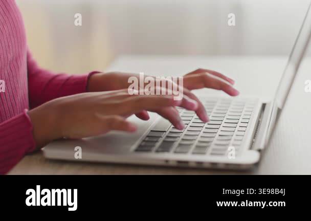 Hands are moving quickly on a laptop keyboard in a well-lit indoor ...