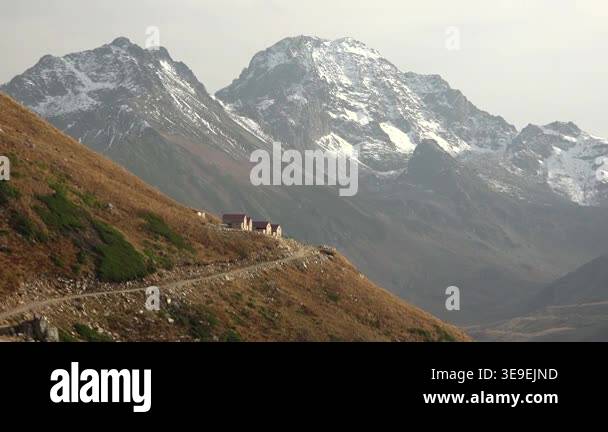 Autumn view chalets on a treeless slope surrounding snowy mountain ...