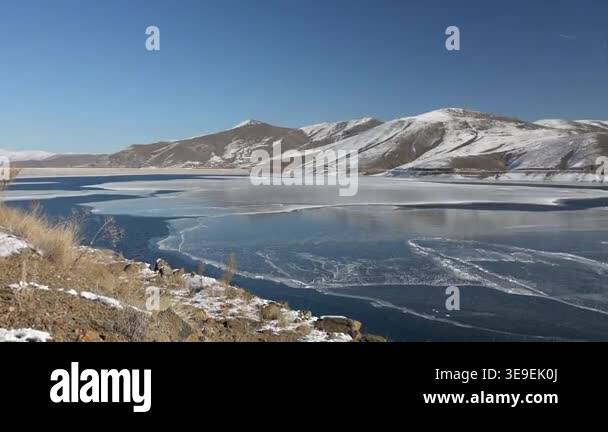 Greenland Arctic bay ice beside treeless hills and snowy slopes under ...