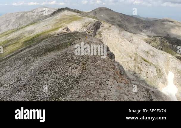 Aerial view shows climbers resting on treeless stony dome mountain peak ...