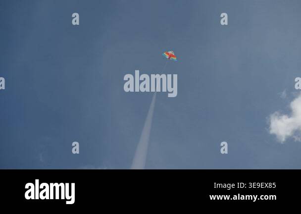 A vibrant kite glides effortlessly in the open sky, creating a peaceful ...