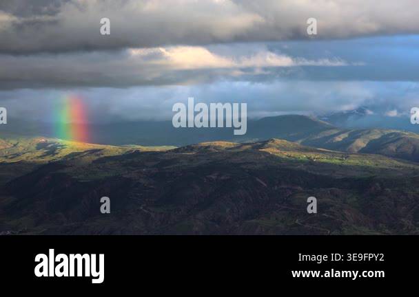 Rainbow appearing after rain over treeless spring hills under dramatic ...