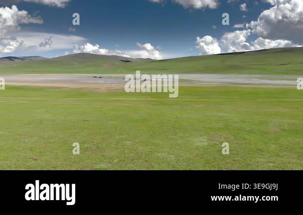 Natural lake between treeless meadows reflects rolling hills beneath a ...