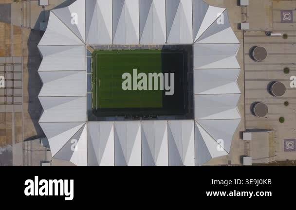Football stadium with white roof and green pitch seen from drone above ...