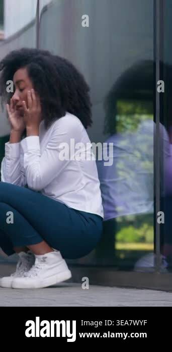 Sad stressed African American business woman sitting outdoors thinking ...
