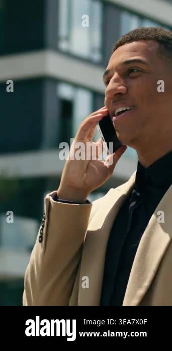 Cheerful African American business man speaking phone walking in city ...