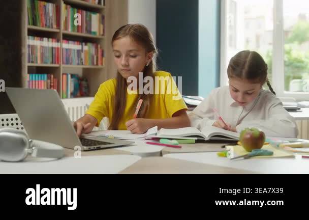 Concentrated two Caucasian little girls children writing homework use ...